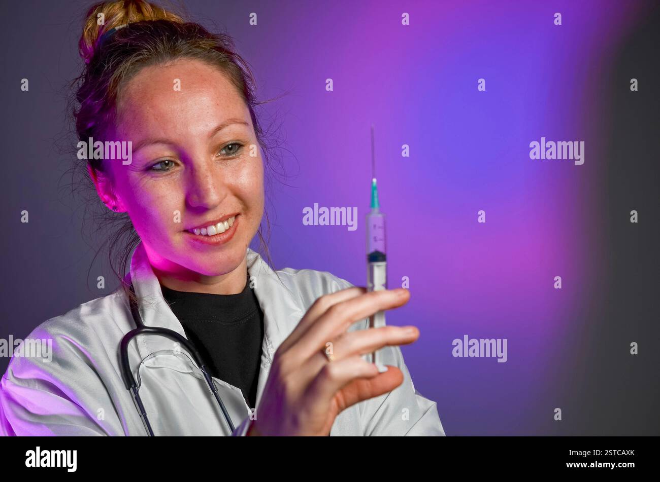 Female doctor smiling and preparing a syringe for injection ...