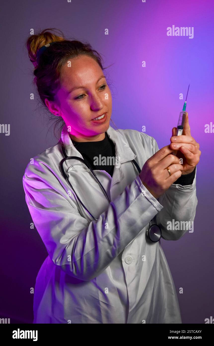 Doctor wearing lab coat and stethoscope preparing a syringe for ...