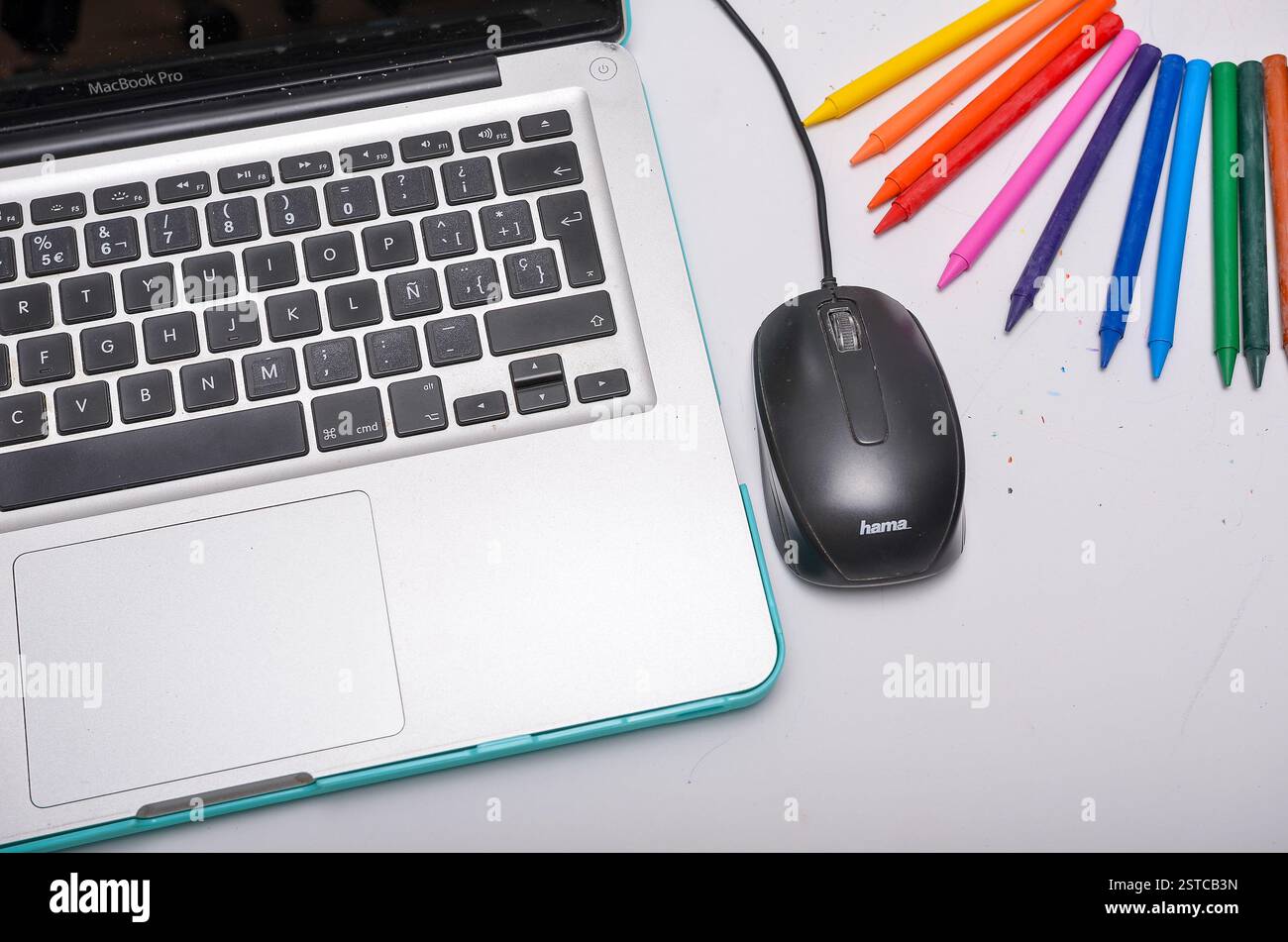 Workplace setting featuring a laptop, mouse, and crayons, suggesting ...