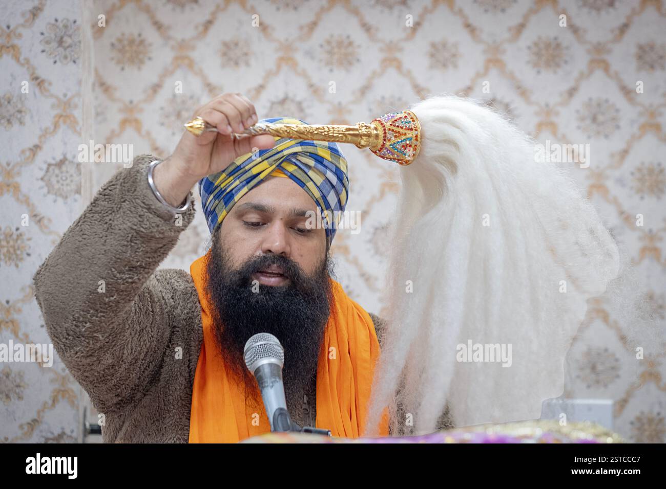 A Sikh priest waves his Chaur Sahib fly whisk at an Akhand Path service ...
