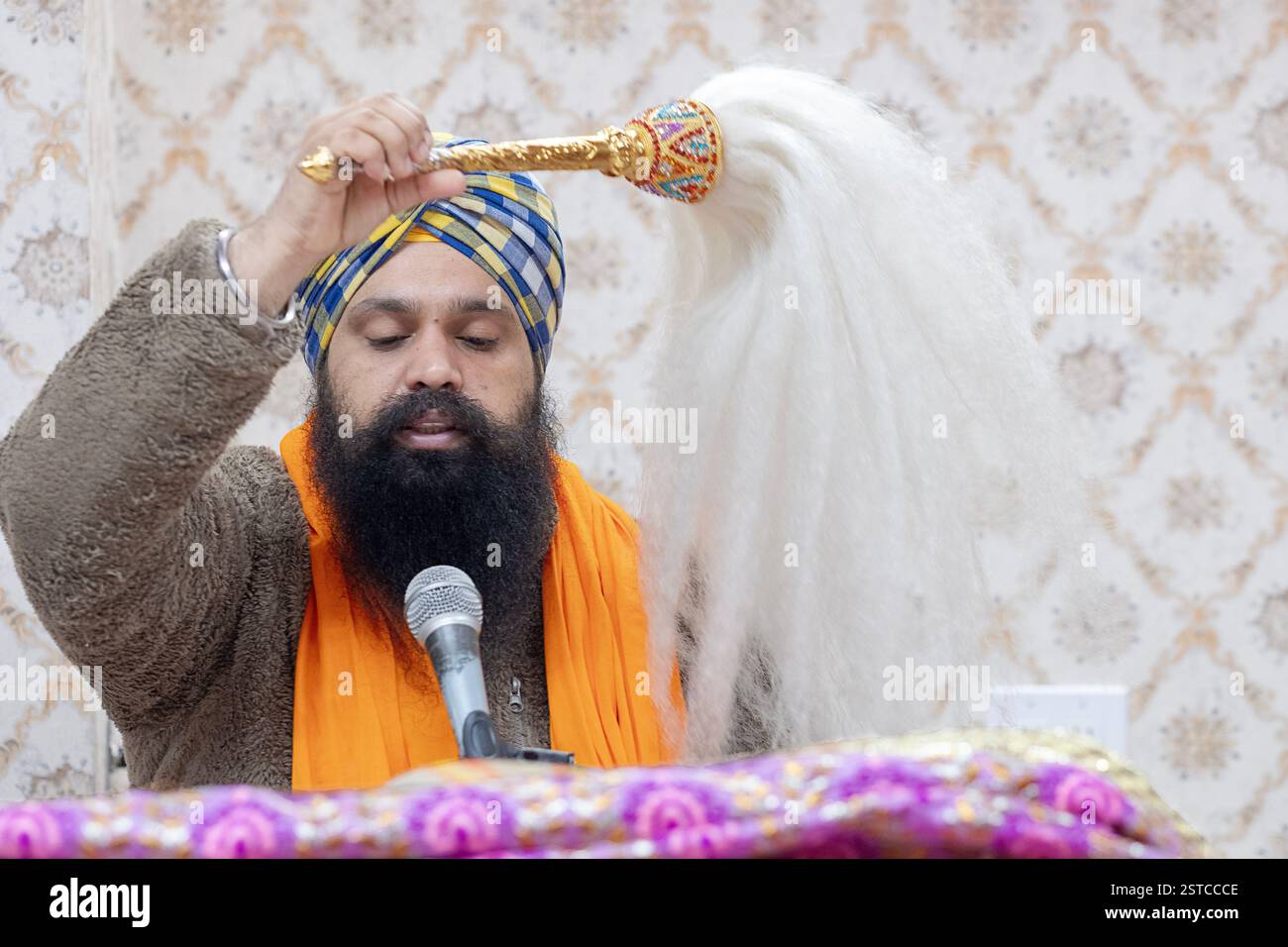 A Sikh priest waves his Chaur Sahib fly whisk at an Akhand Path service ...