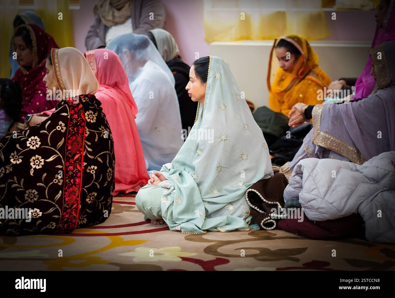 Seated worshippers at a temple with a spotlight on a pretty one in a ...