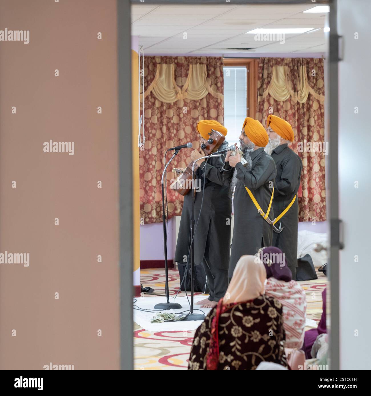 A kirtan dhadi music group at a Sikh temple as seen through an open ...