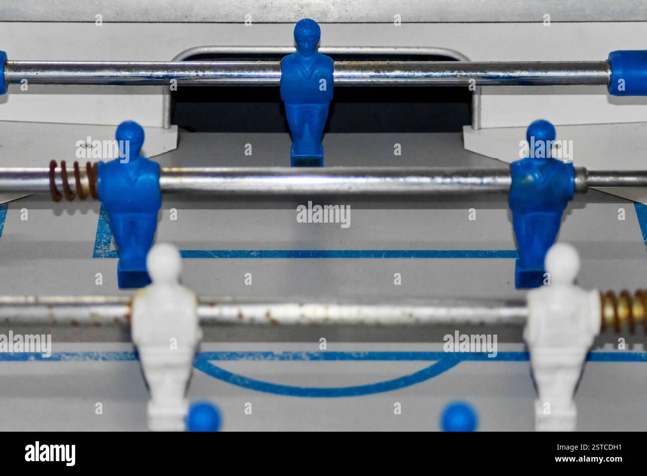 The image highlights foosball players on a grey playing field with blue ...