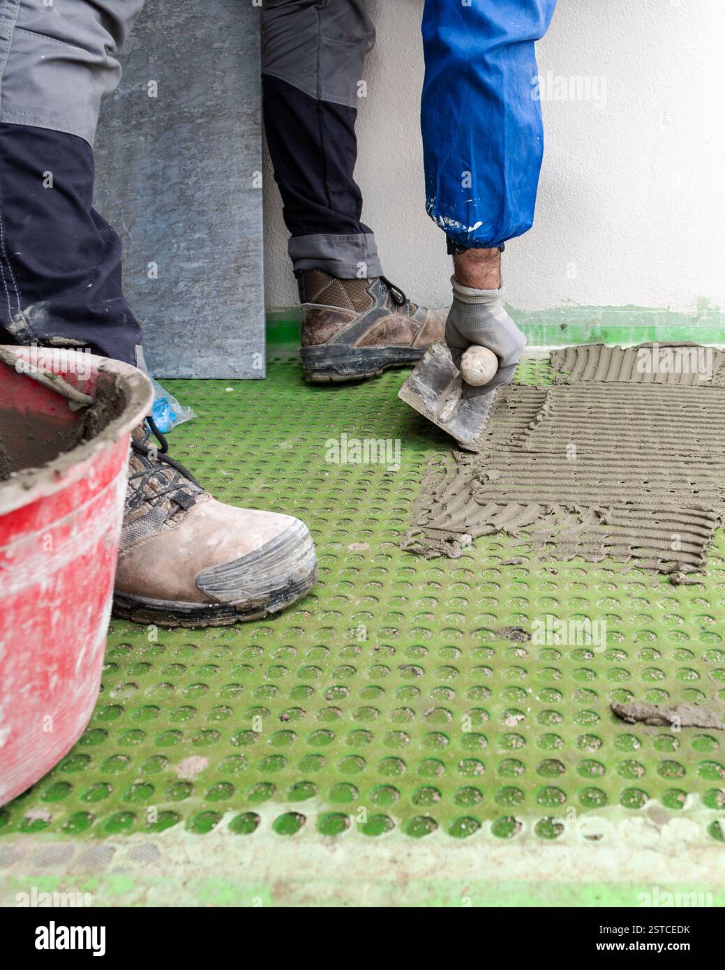 Bricklayer tiler spreads glue with notched trowel to install tiles for ...