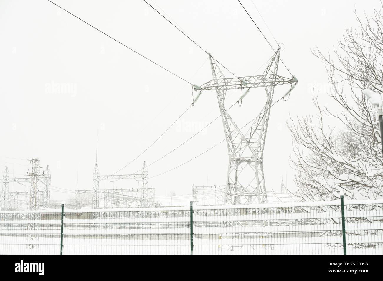 A large electrical pylon and power lines covered in snow stand against ...