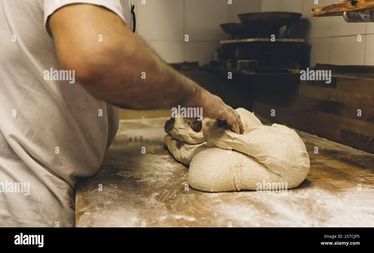 Baker expertly kneading dough on a floured wooden surface, showcasing ...