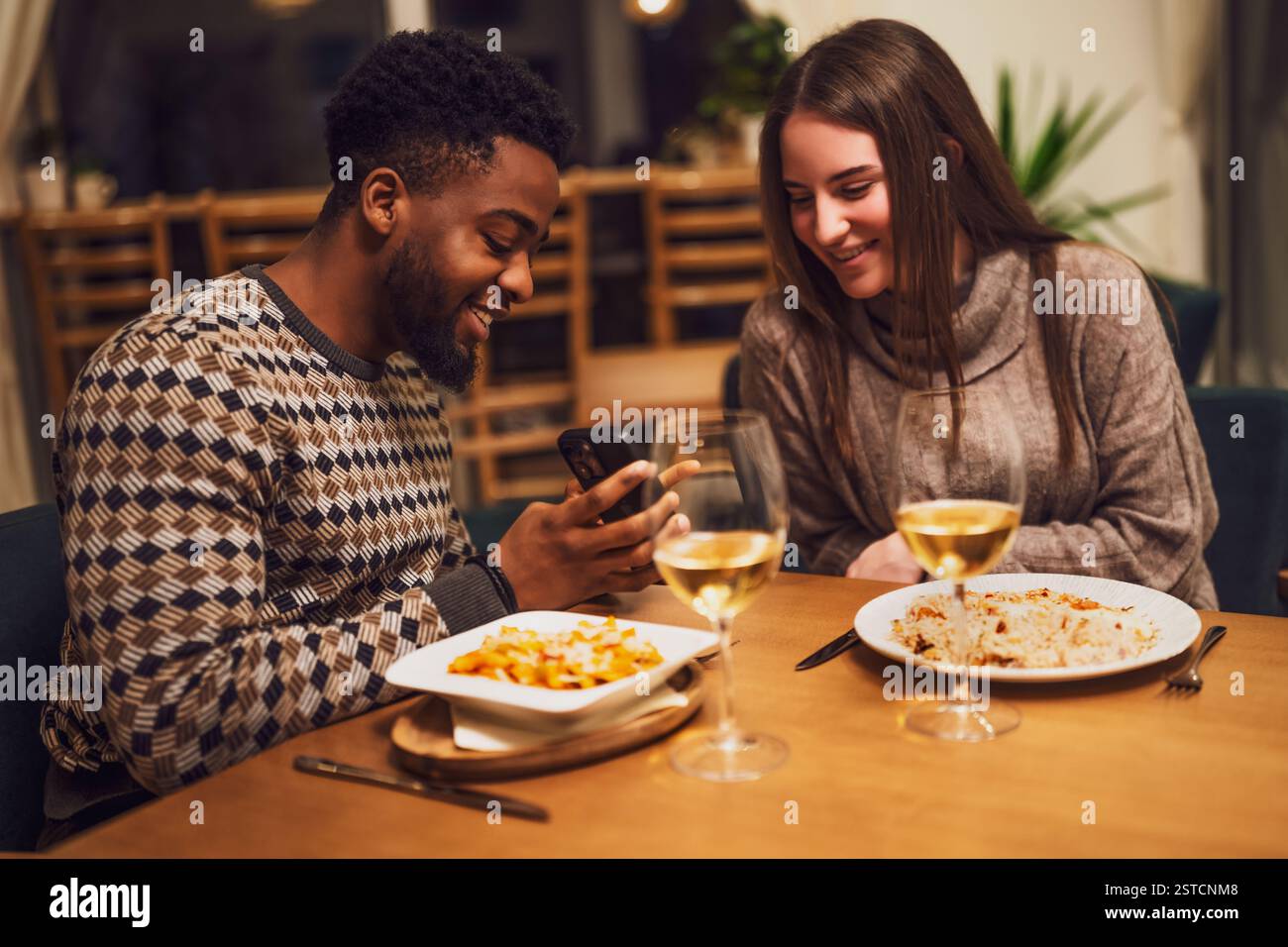Two friends are having dinner at restaurant. They are using smartphone ...