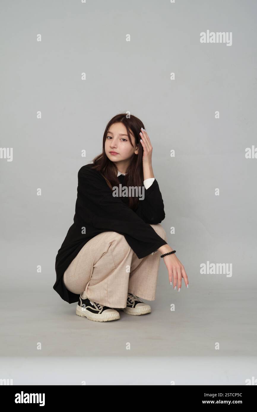 Thoughtful teen girl sits contemplatively, her somber expression ...