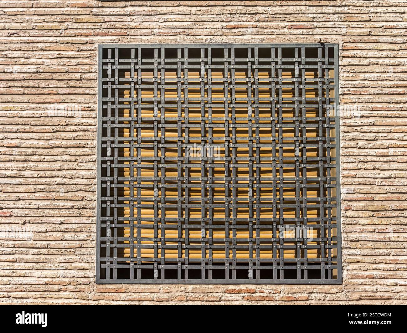 Brick wall with a window secured by intricate black metal bars ...