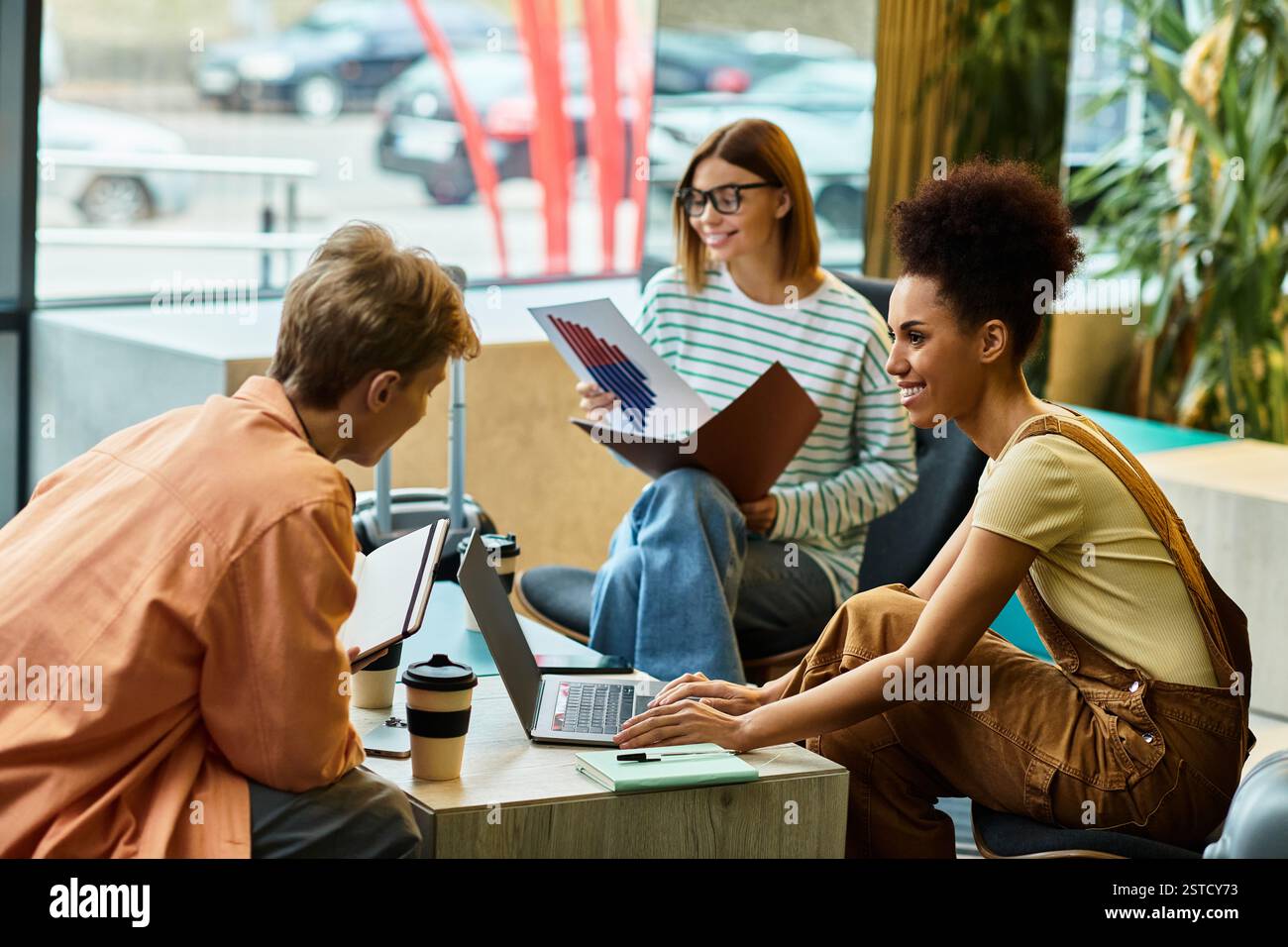 Three colleagues engage in a lively discussion while working on their ...
