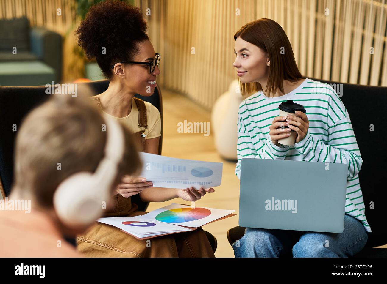 Two colleagues animatedly share ideas while one enjoys a drink Stock ...