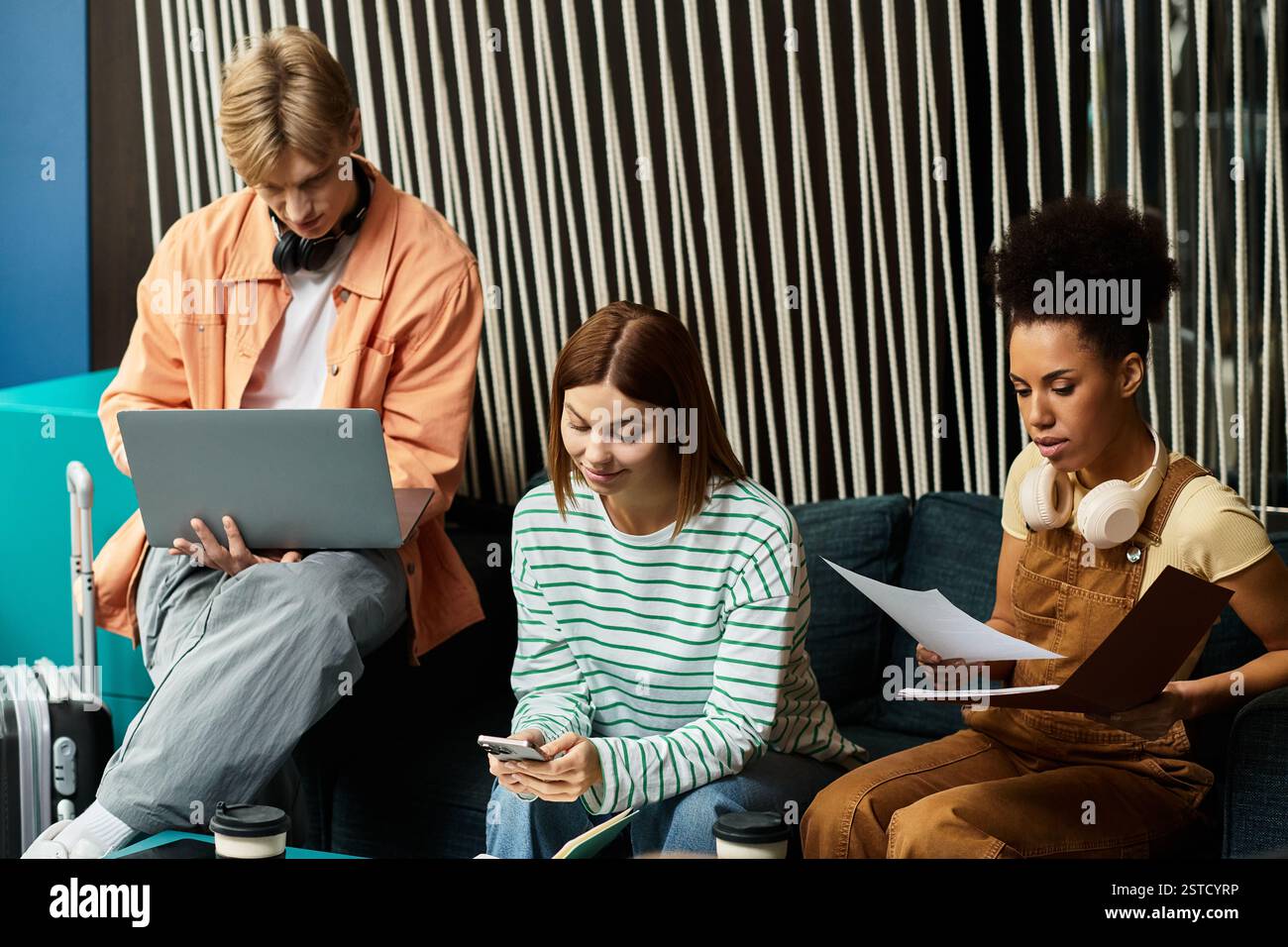 Three colleagues engage in various tasks using devices while relaxing ...