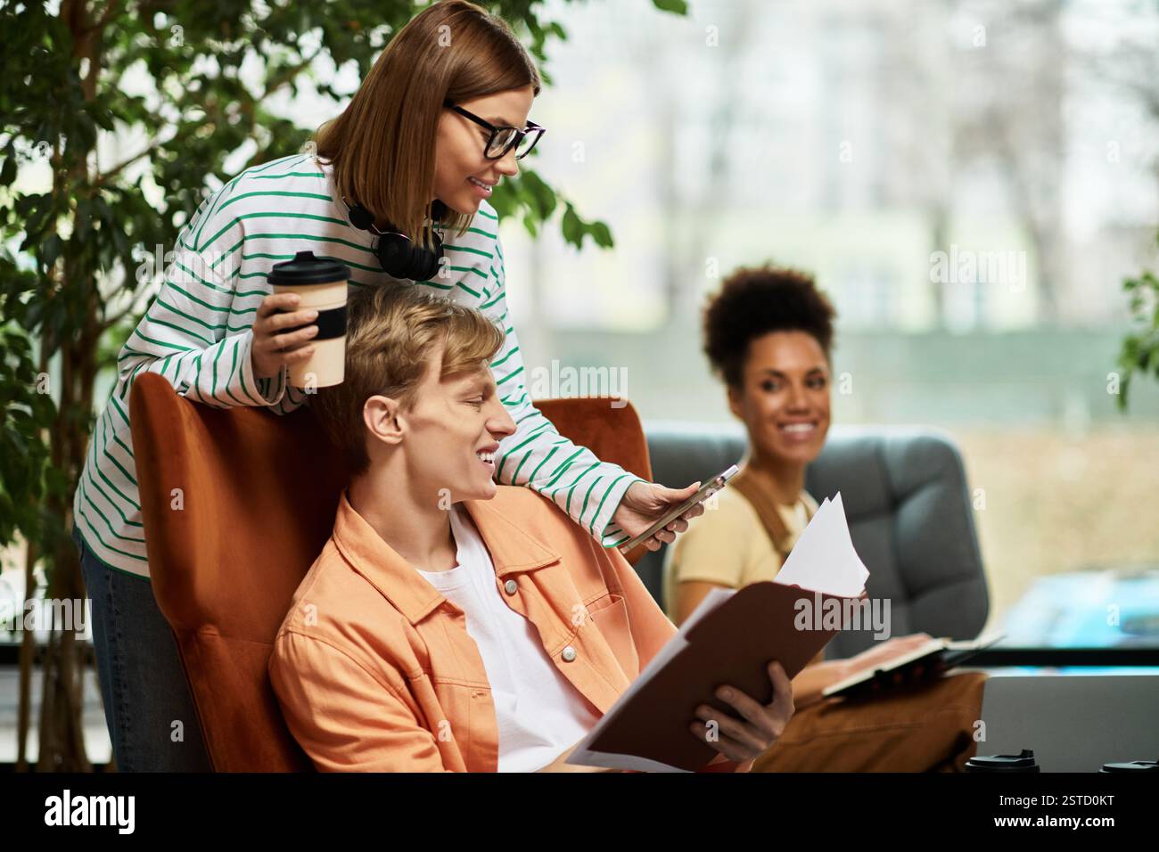 Engaged in work, three colleagues share ideas and laughter while seated ...