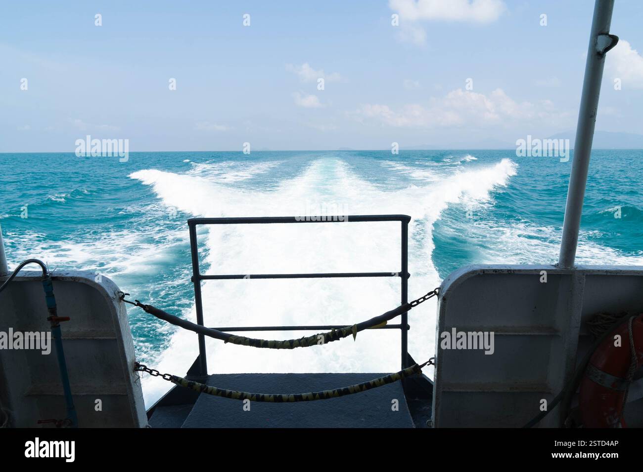 A vessel glides through serene blue waters, leaving soft white waves in ...