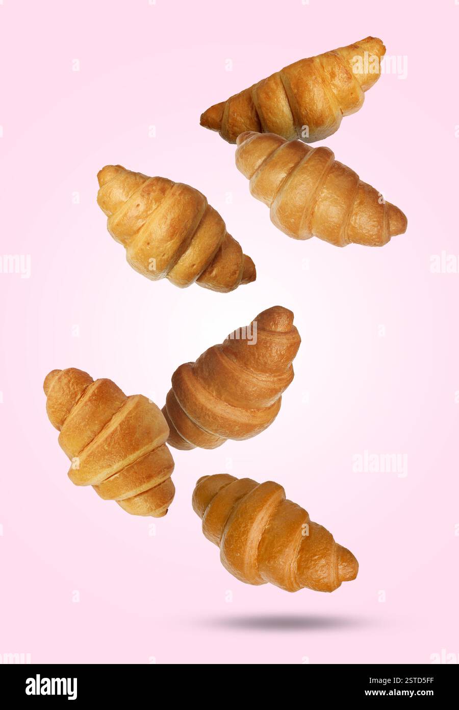 Delicious croissants falling on pink background. Puff pastry Stock ...