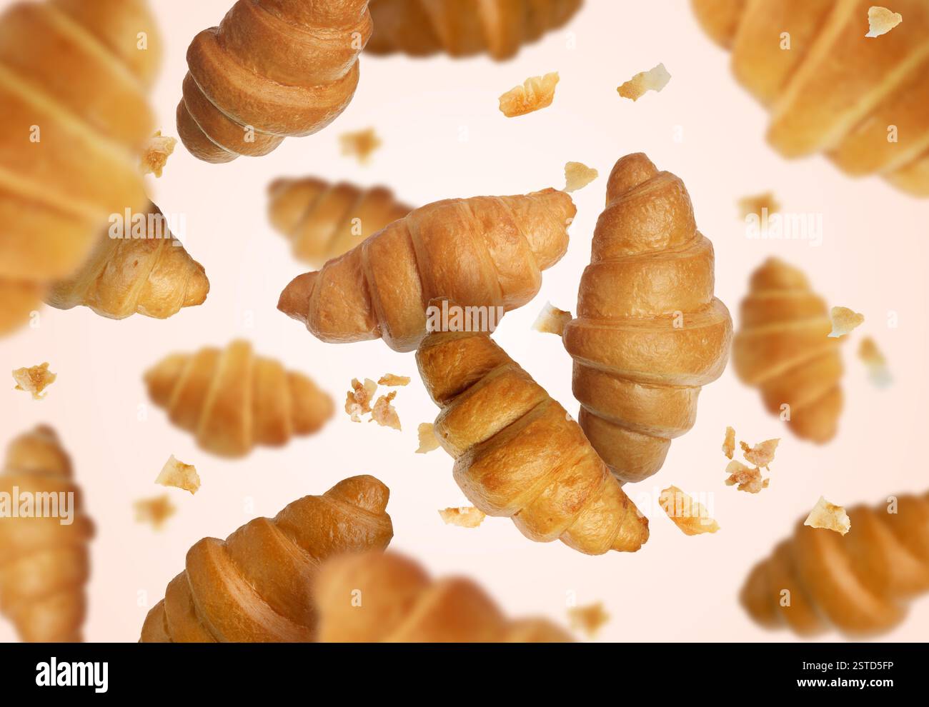 Delicious croissants and crumbs in air on white background. Puff pastry ...