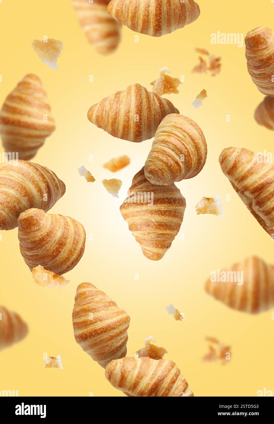 Delicious croissants and crumbs in air on golden background. Puff ...