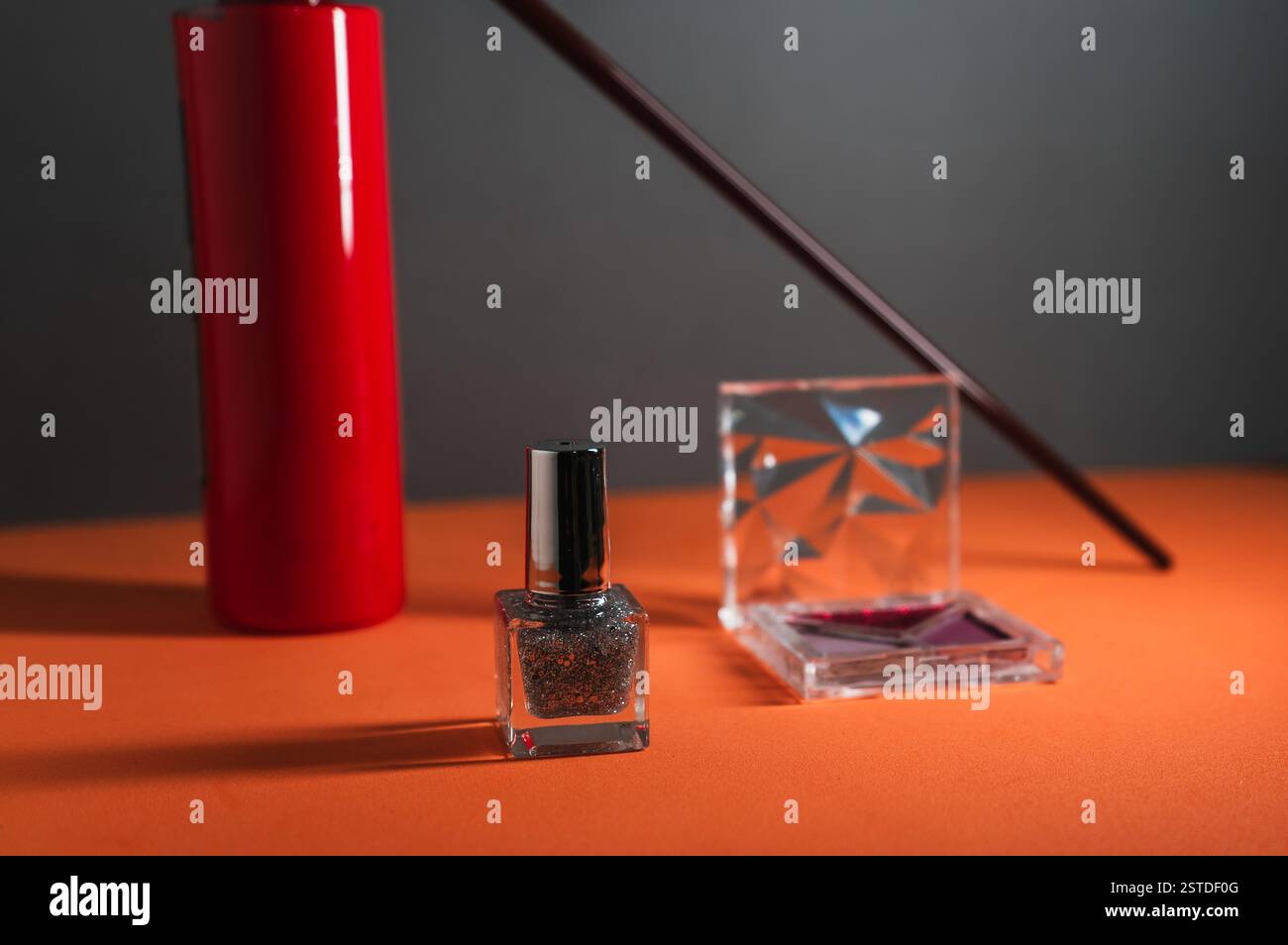 Collection of cosmetics featuring red and glittery nail polish with ...