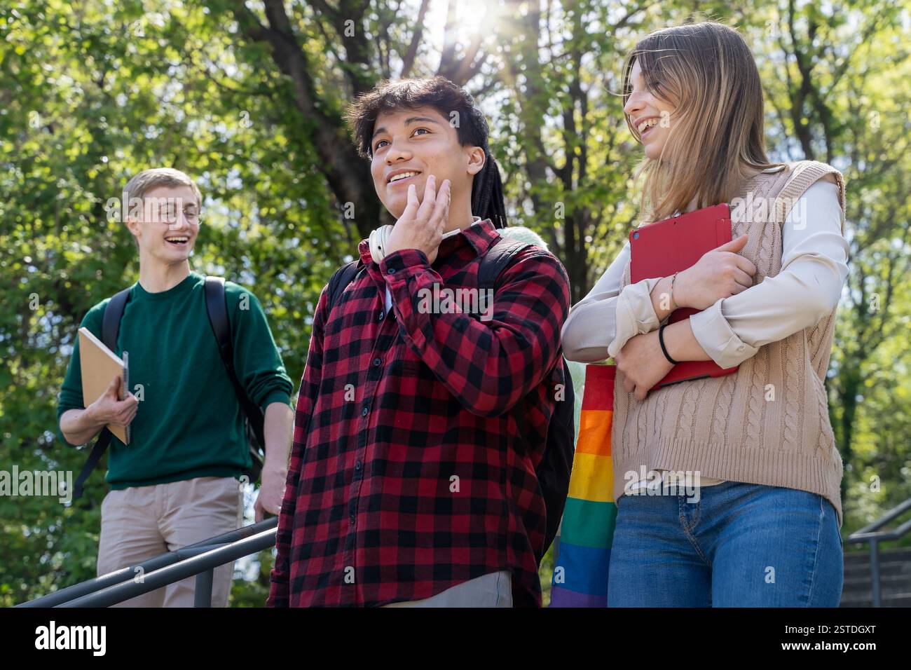 A diverse group of students walking outdoors, carrying laptops and a ...