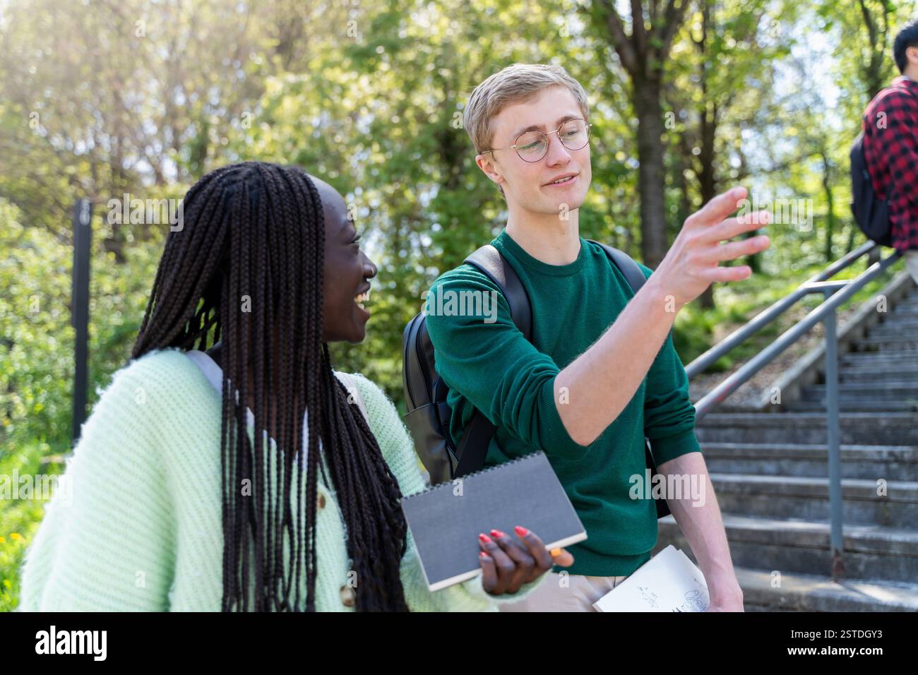 Two university students engaged in a conversation while taking notes in ...