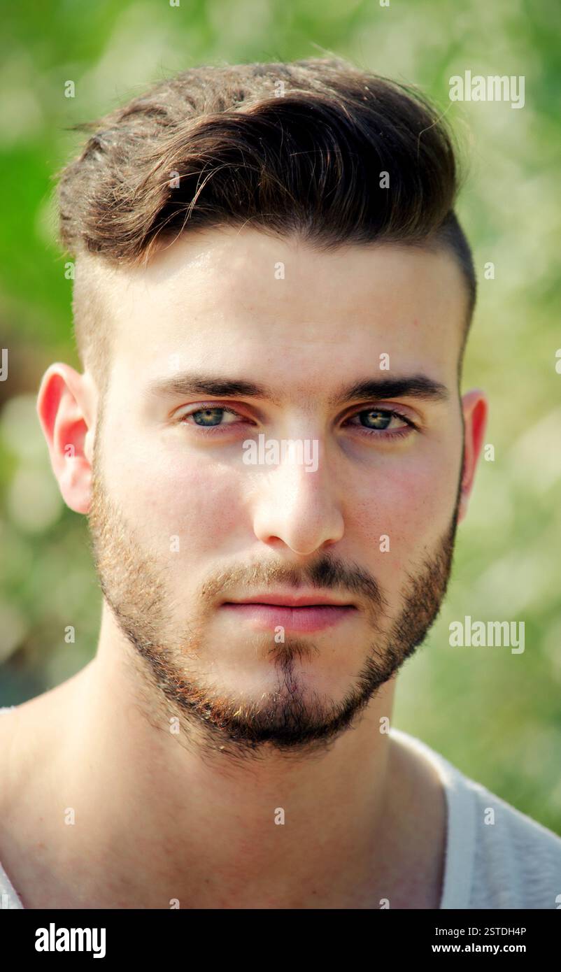 Headshot of handsome young man outdoors, serious expression Stock Photo ...