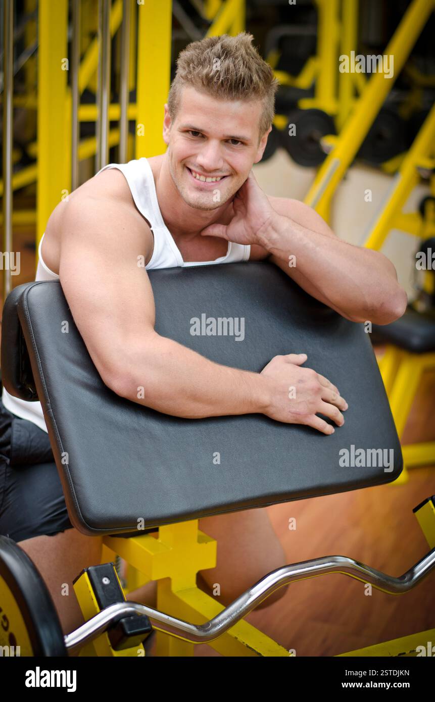Attractive young man smiling on gym equipment Stock Photo - Alamy