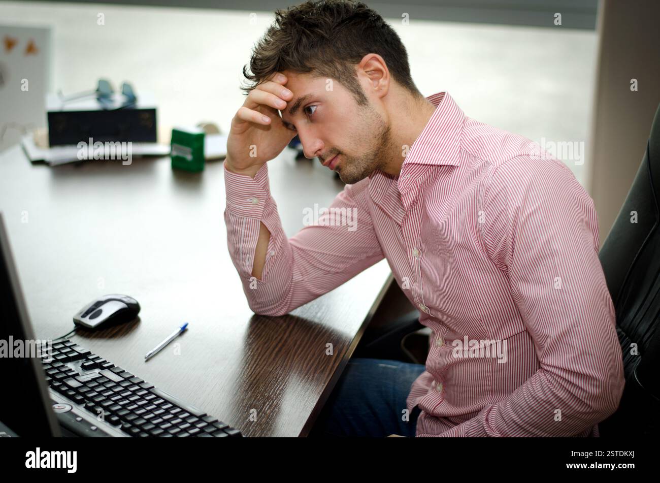 Preoccupied, worried young male worker staring at computer screen in ...