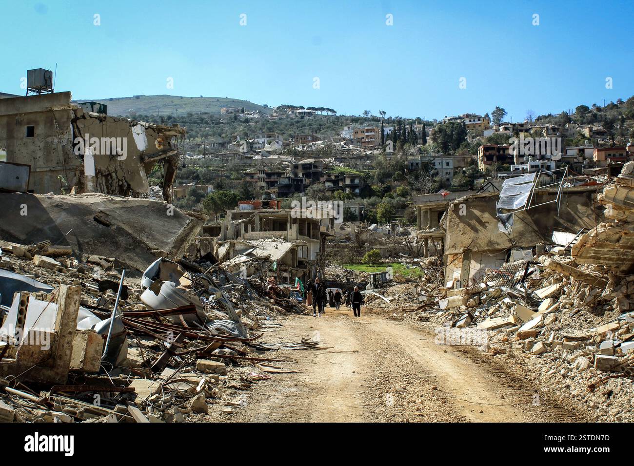 Kfarkela, Lebanon. 18th Feb, 2025. Lebanese villagers walk among debris ...