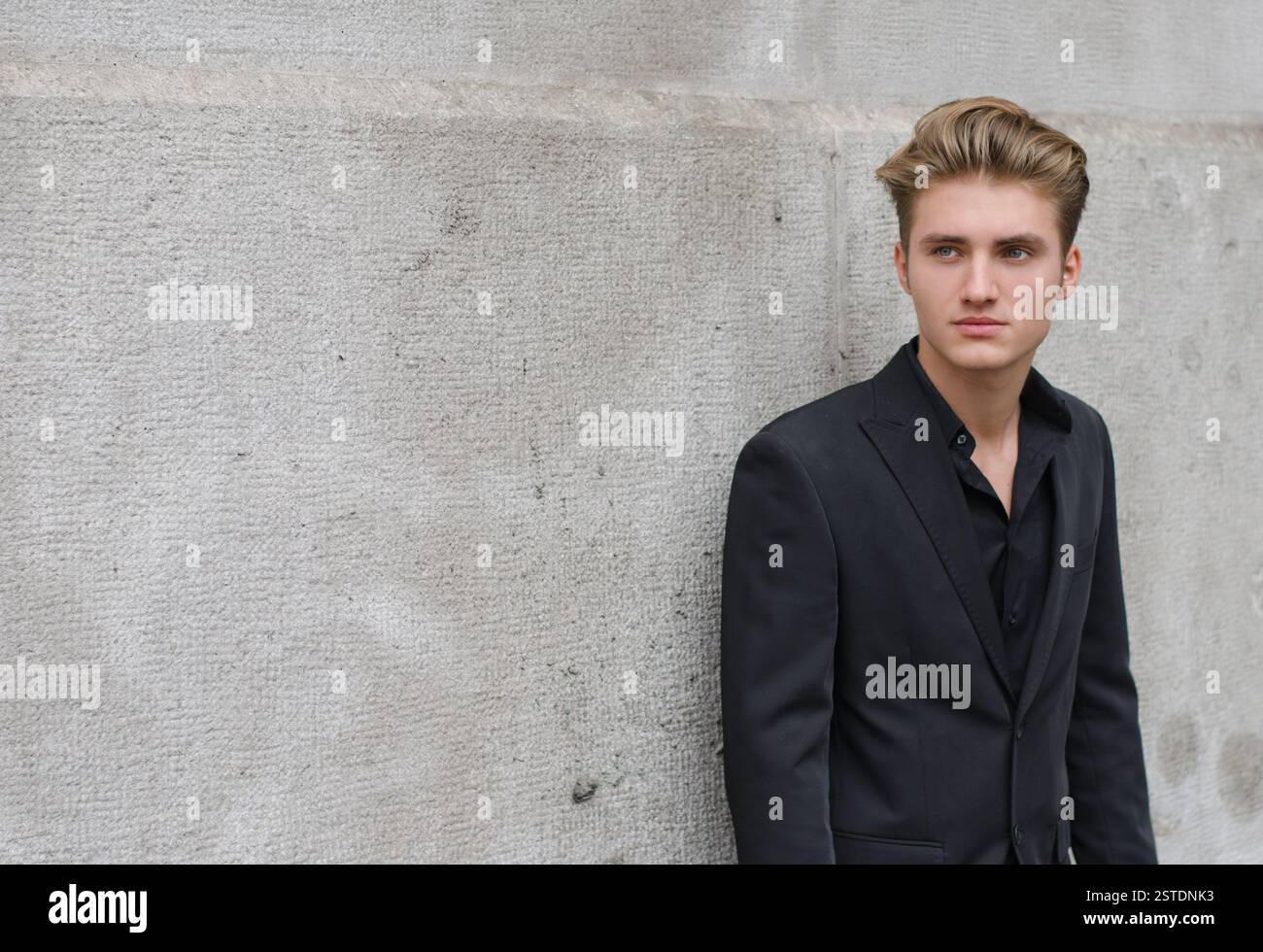 Attractive blue eyed, blond young man leaning with his back against ...
