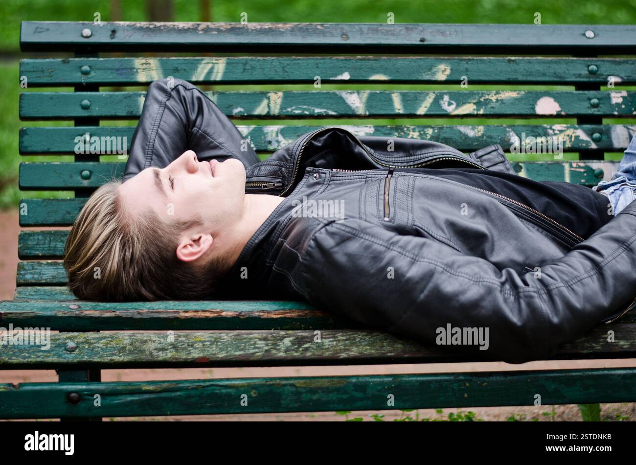Attractive blue eyed, blond young man laying on park bench Stock Photo ...