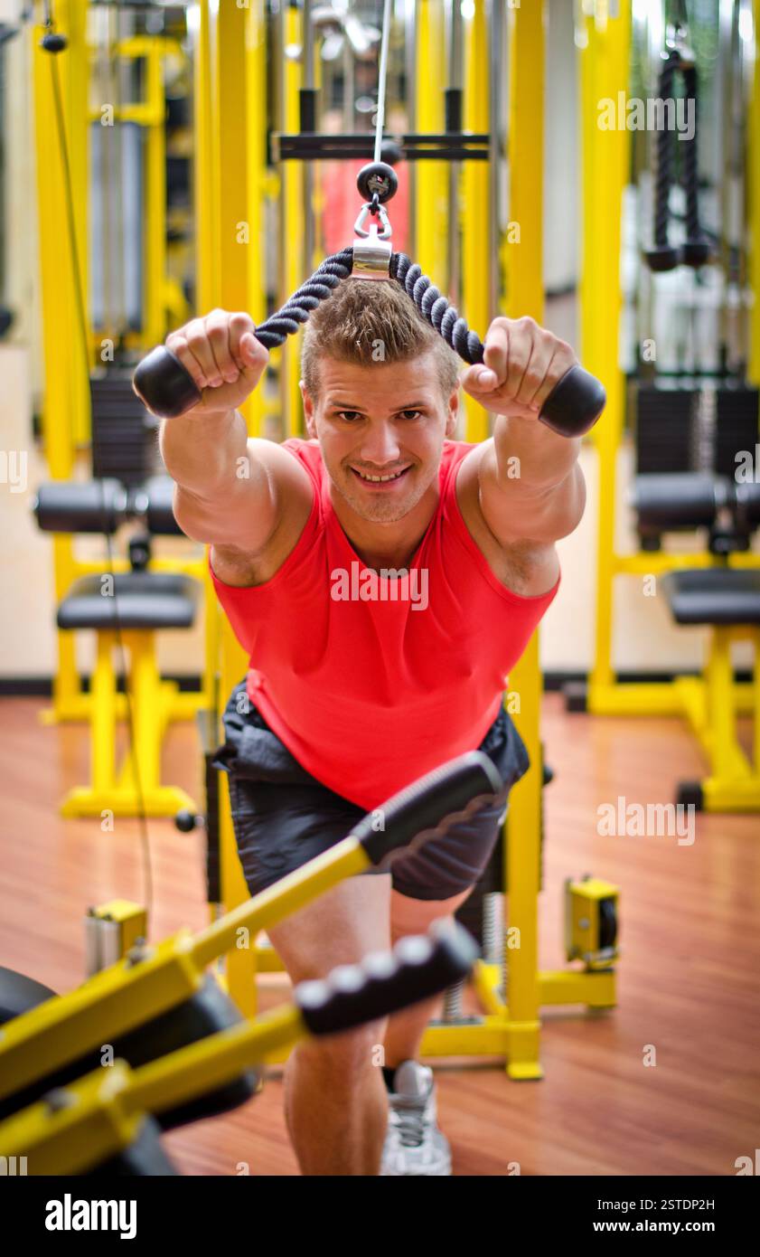 Young man training on gym equipment, pulling handle on cables Stock ...