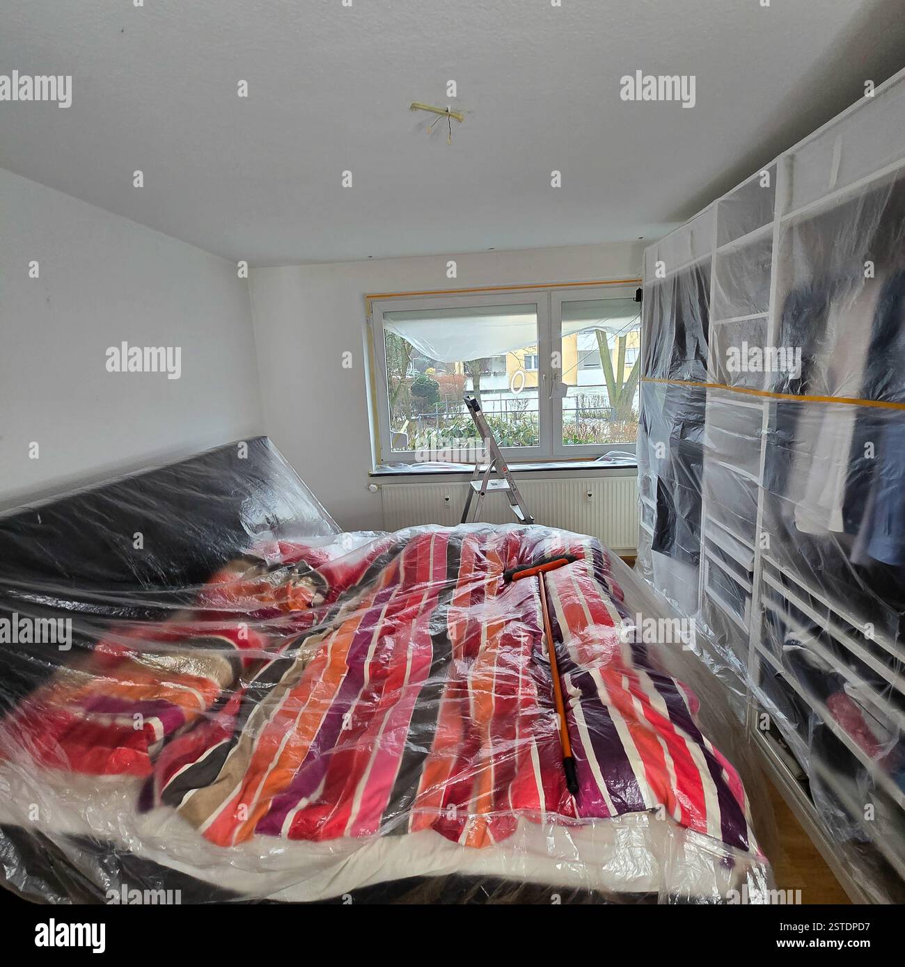 A modern bedroom setup featuring plastic protection to ensure the space ...