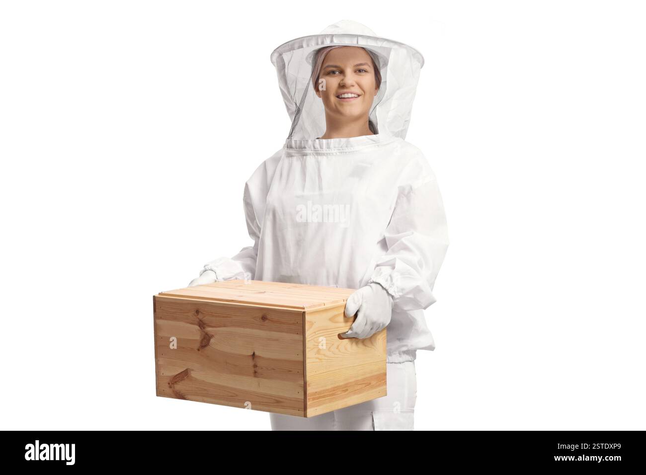 Young female bee keeper in a uniform holding a wooden crate isolated on ...