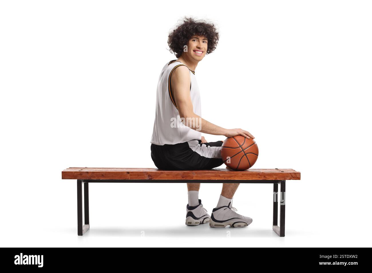 Basketball player sitting on a bench with a ball and smiling isolated ...