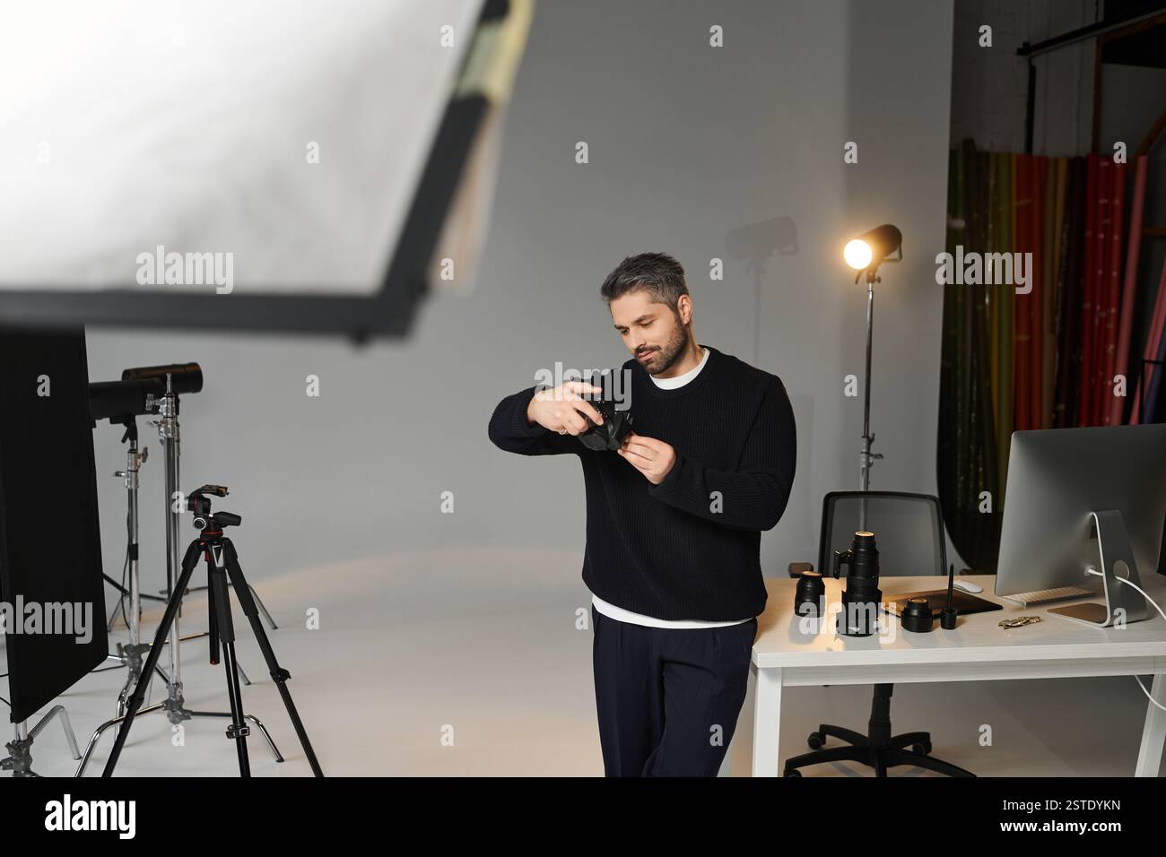 Focused professional adjusts camera settings in a modern studio filled ...