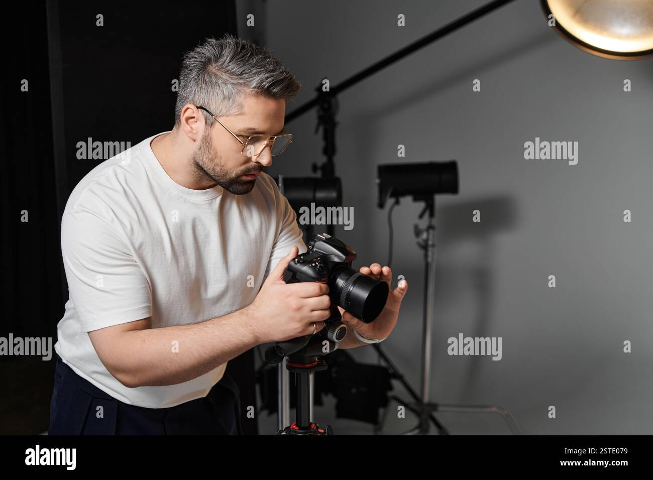 A dedicated professional adjusts his camera while focused on creating ...