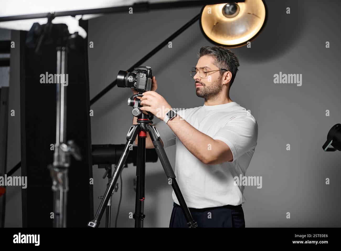 A skilled individual adjusts a camera on a tripod, ready for an exciting session in a studio ...