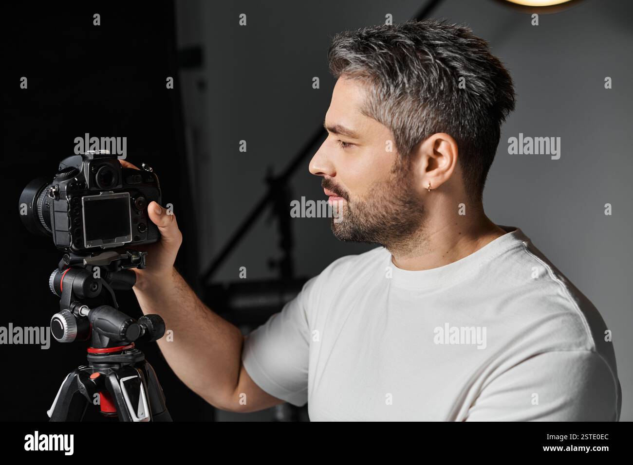A man concentrates on adjusting his camera settings while standing in a ...