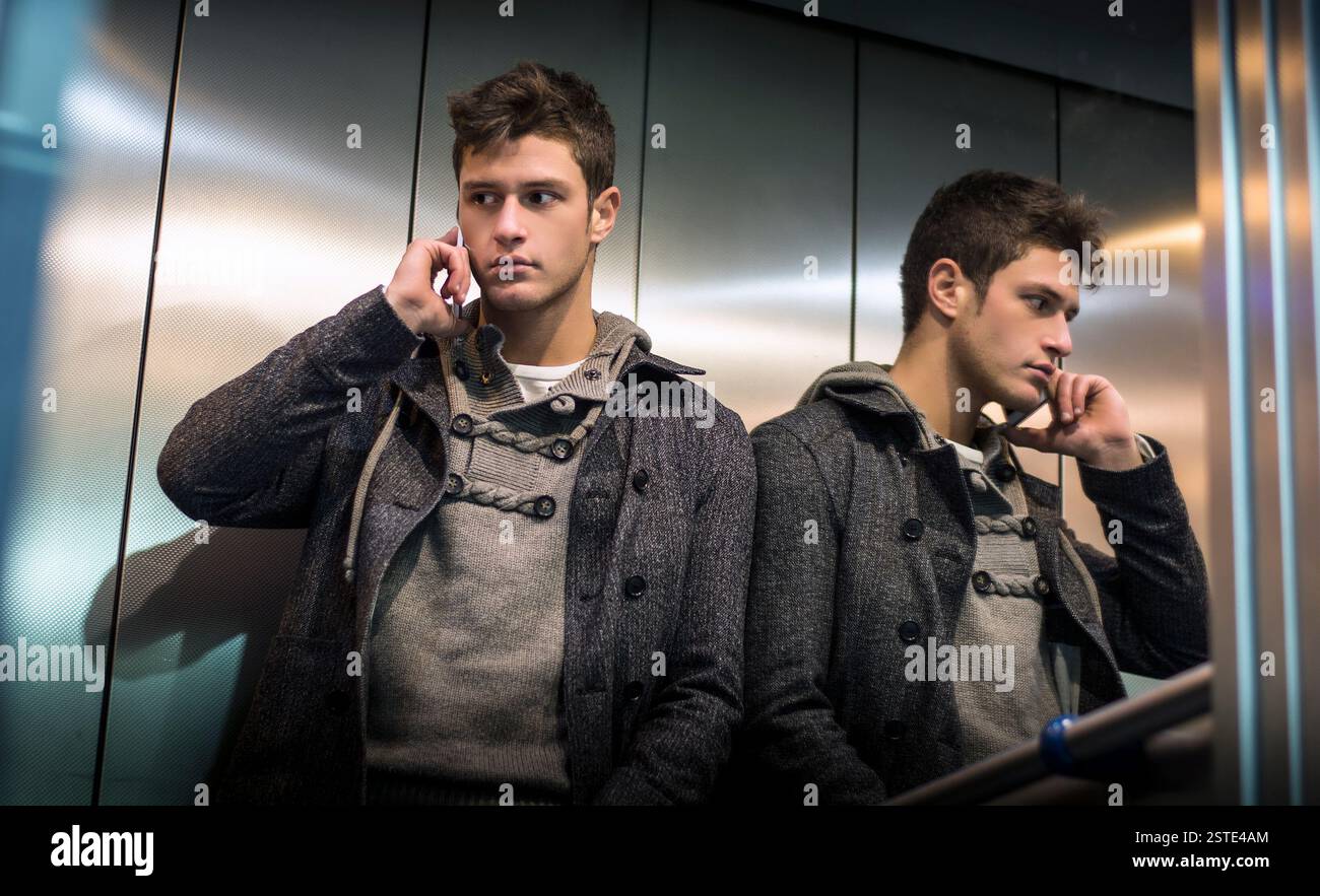 Handsome young man in elevator (lift) using cell phone Stock Photo - Alamy