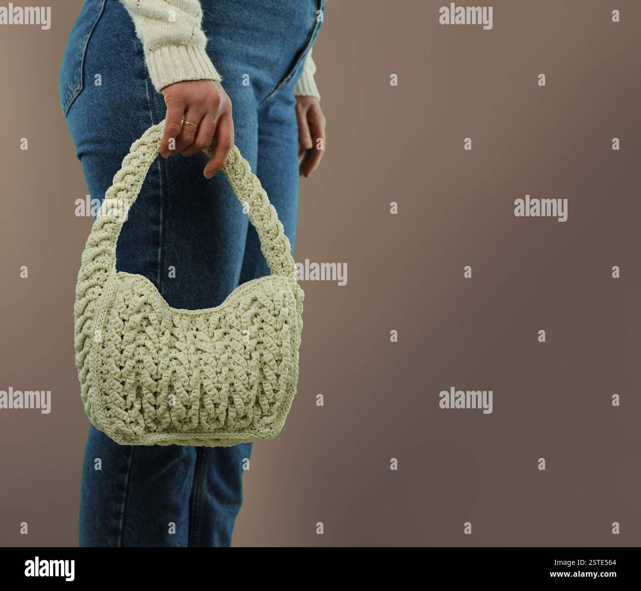 Woman with beige knitted bag in front of brown background. World ...