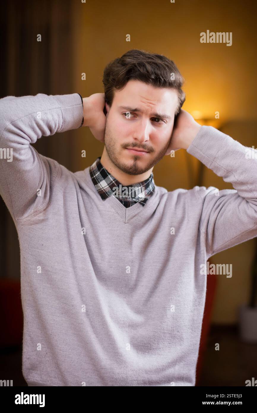 Handsome young man covering his ears Stock Photo - Alamy