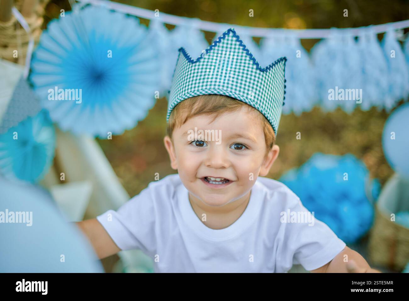 Smiling toddler boy at an outdoor celebration, wearing a checkered ...