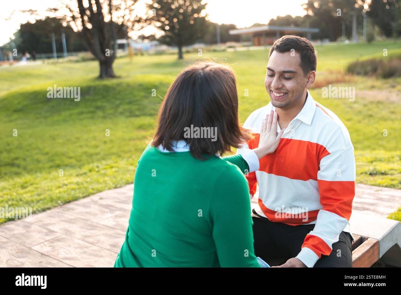 A young Latin couple shares a tender moment outdoors, with warm ...