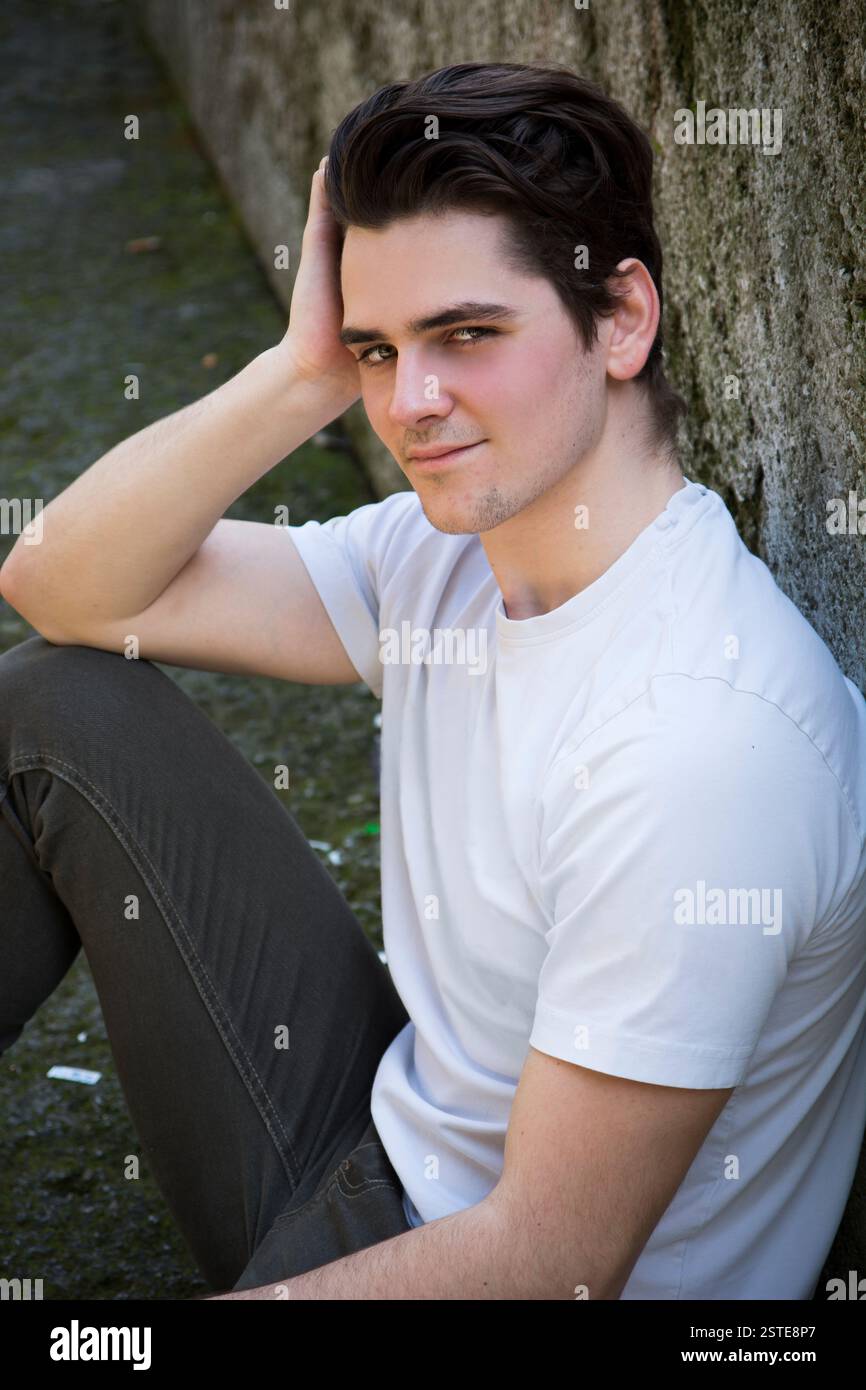Attractive young man sitting on the ground against rock outdoors Stock ...