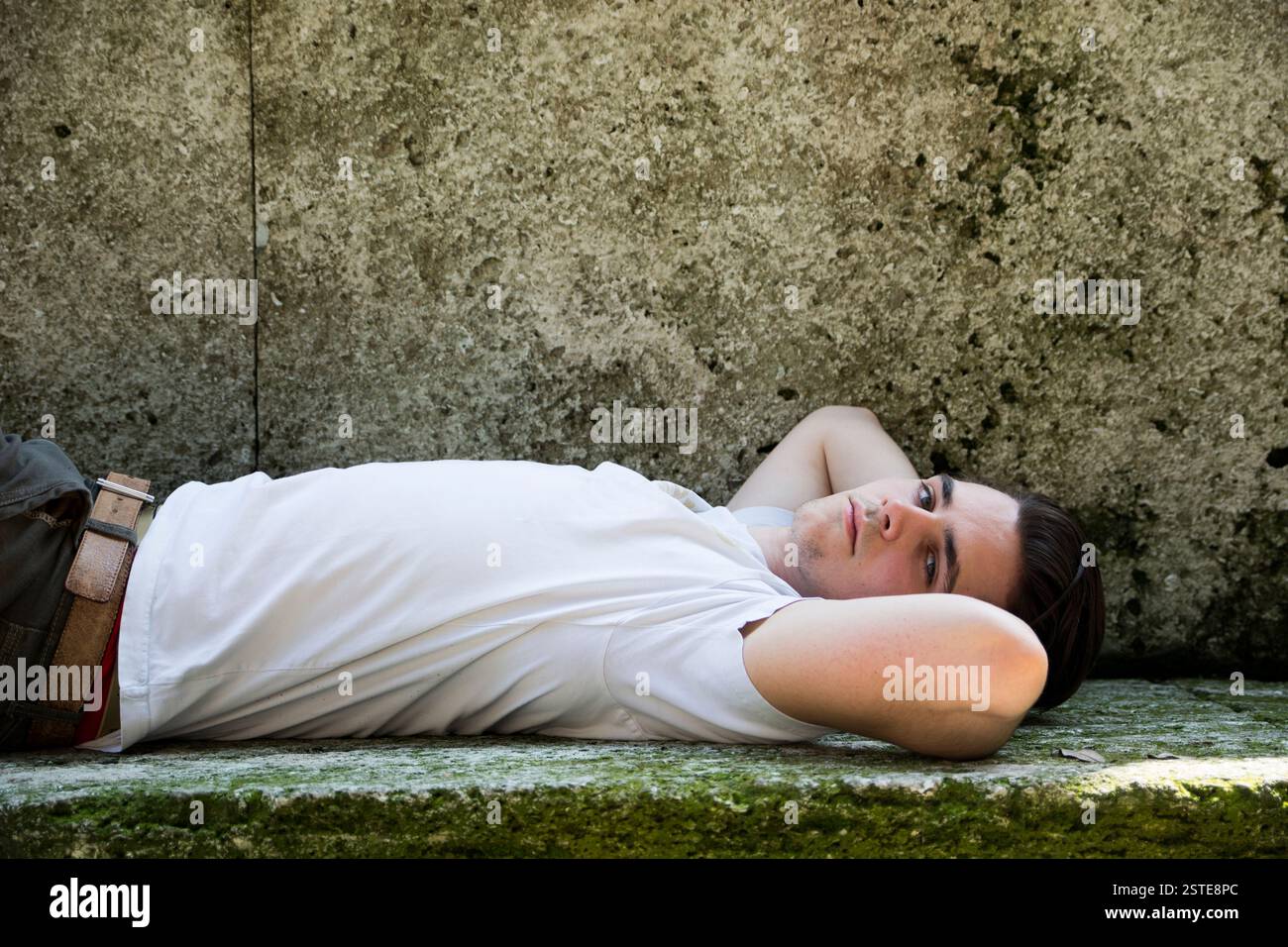 Handsome young man lying down on stone blocks Stock Photo - Alamy