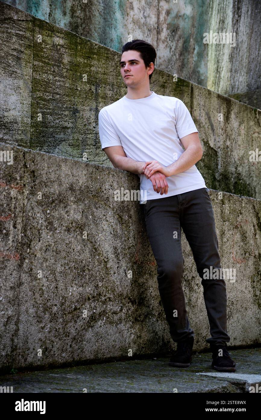Handsome young man standing and leaning on stone blocks hi-res stock ...