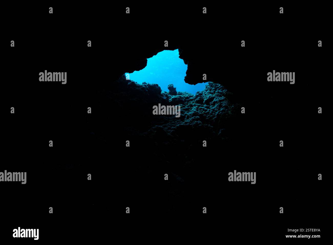 Underwater view of narrow dark cave with rough rocky formation undersea ...