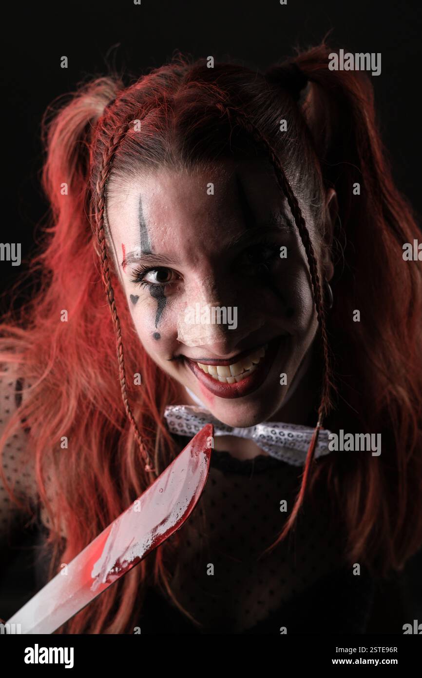 A woman with red hair smiles menacingly holding a bloody knife ...