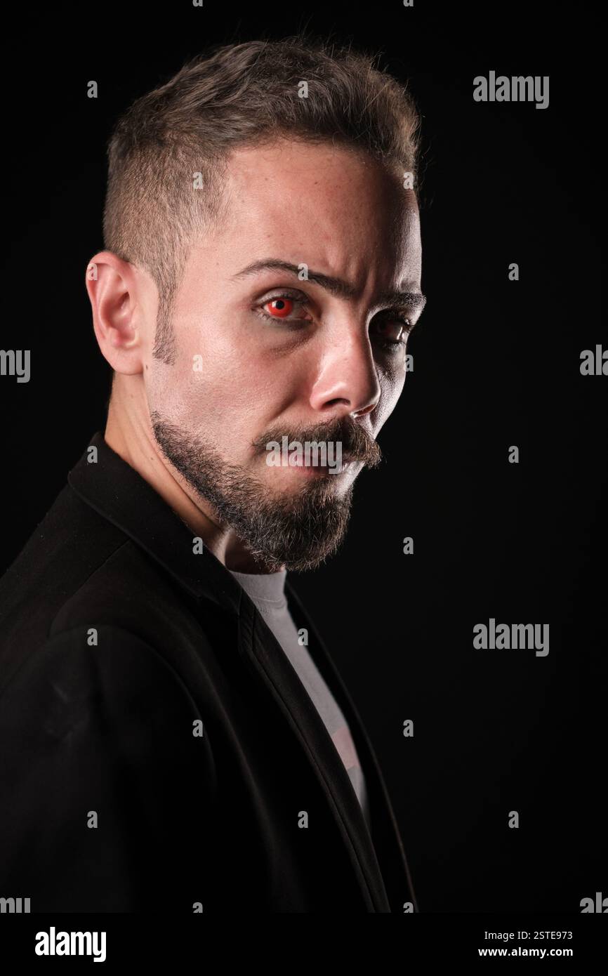 A portrait of a man with a striking stare with red contact lenses and ...